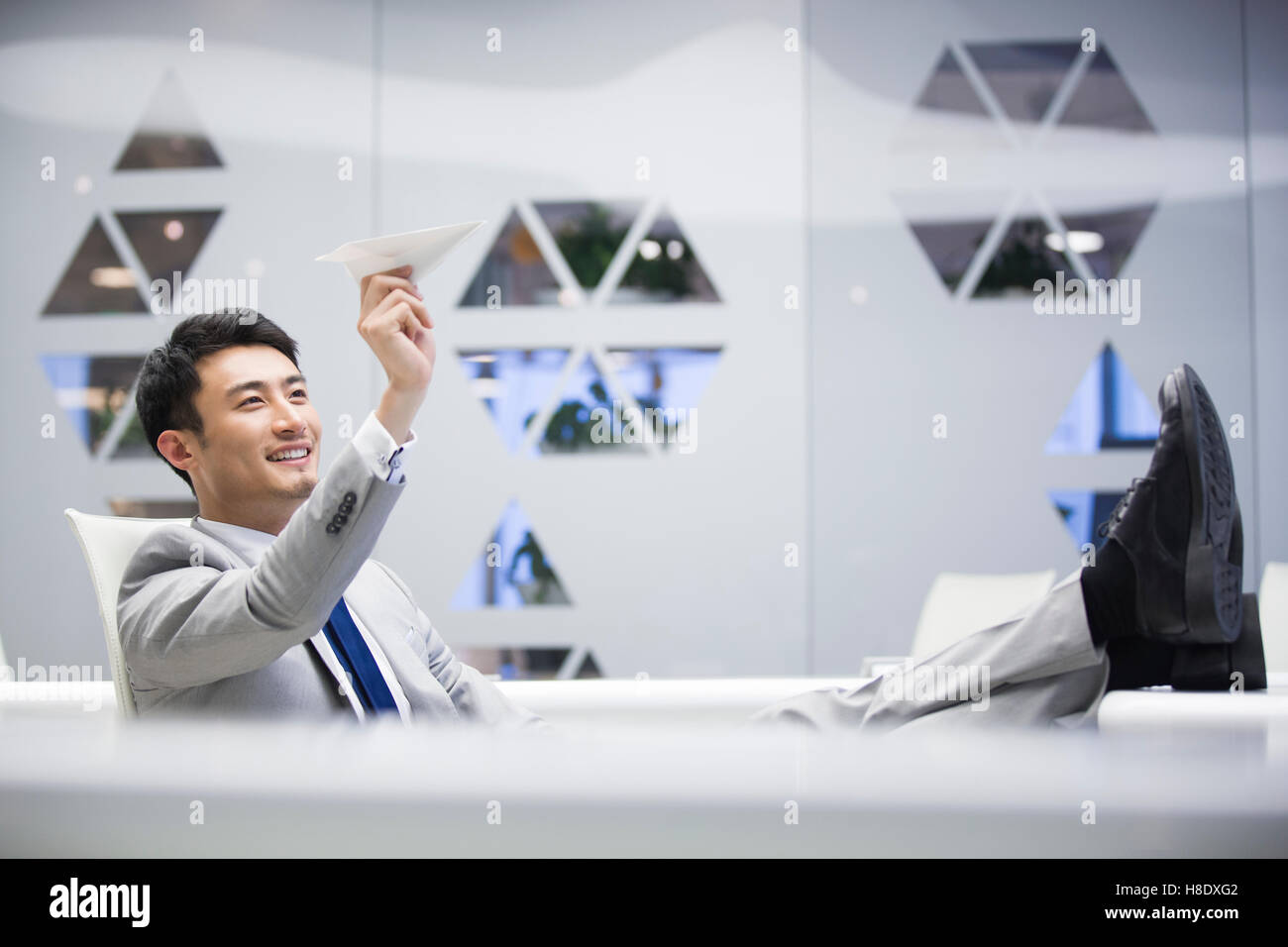Young Chinese businessman flying a paper airplane Stock Photo - Alamy