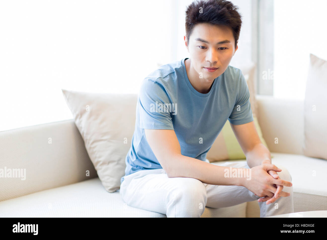 Young Chinese man thinking on the sofa Stock Photo - Alamy