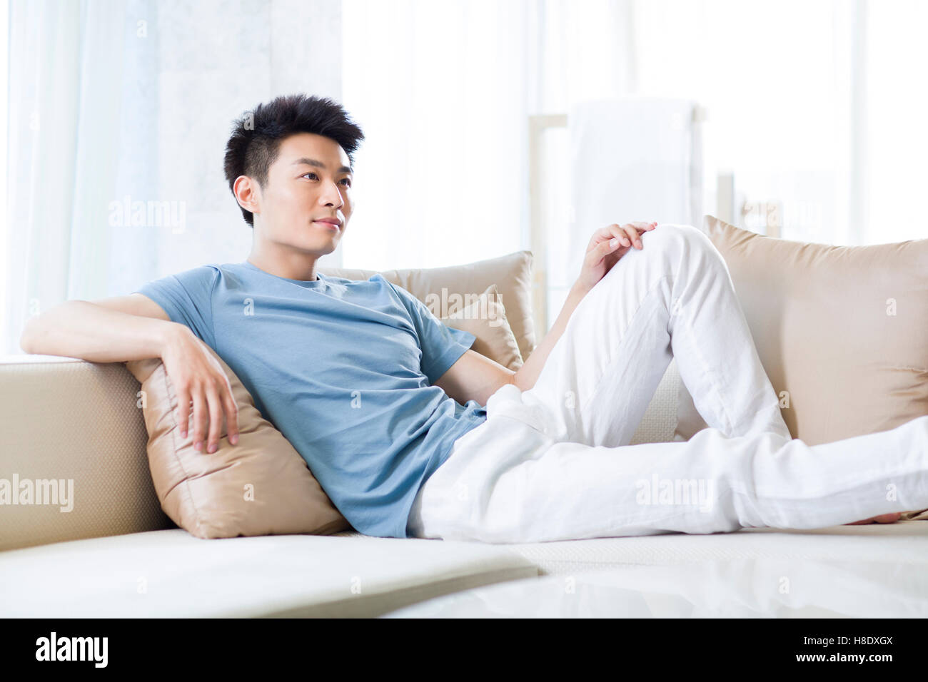 Young Chinese man relaxing on the sofa Stock Photo - Alamy