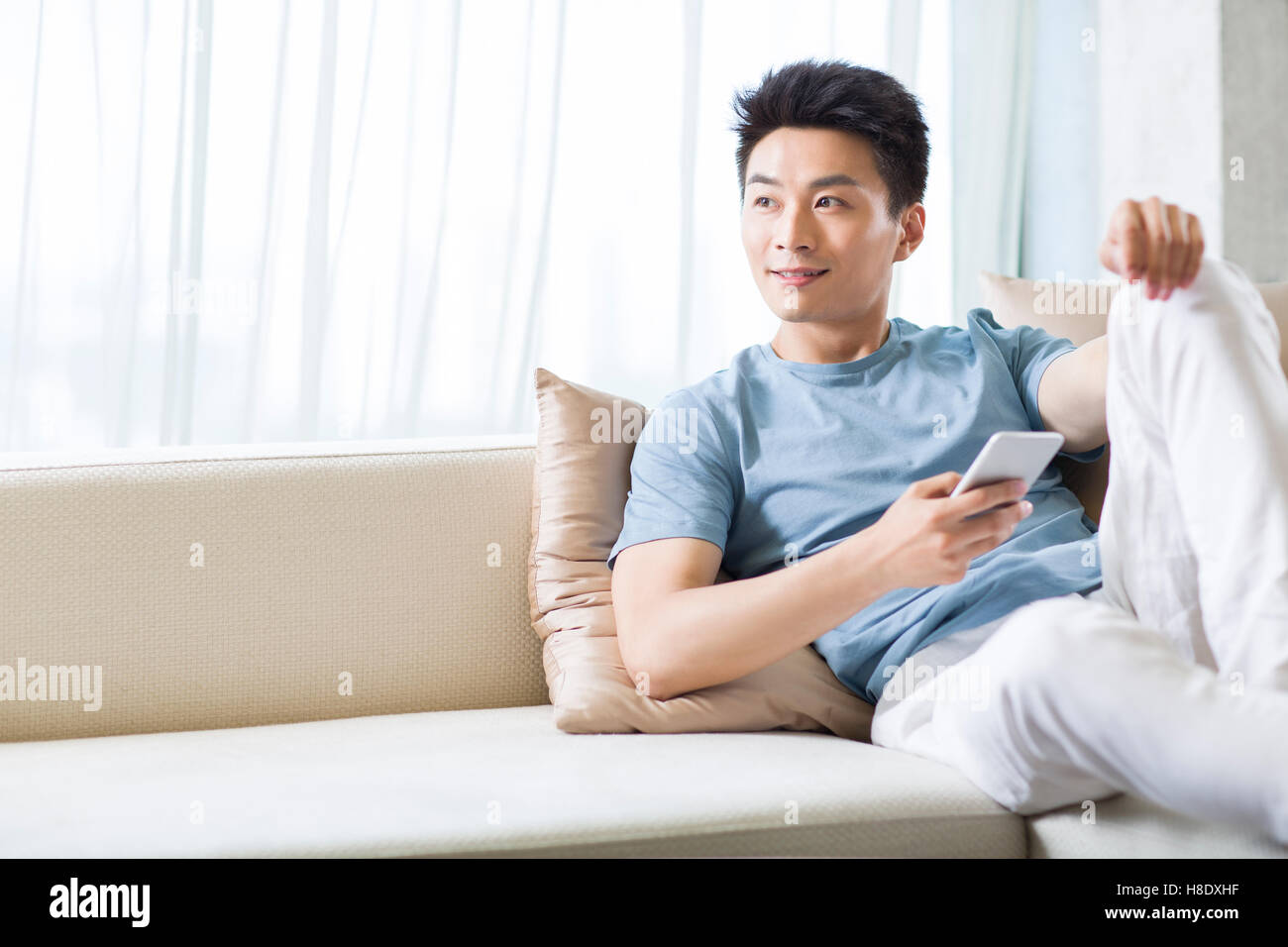 Young Chinese man relaxing on the sofa Stock Photo - Alamy