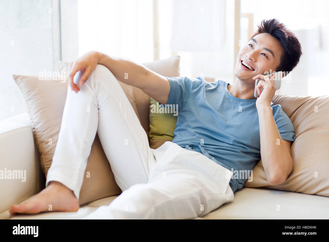 Young Chinese man talking on cell phone at home Stock Photo - Alamy