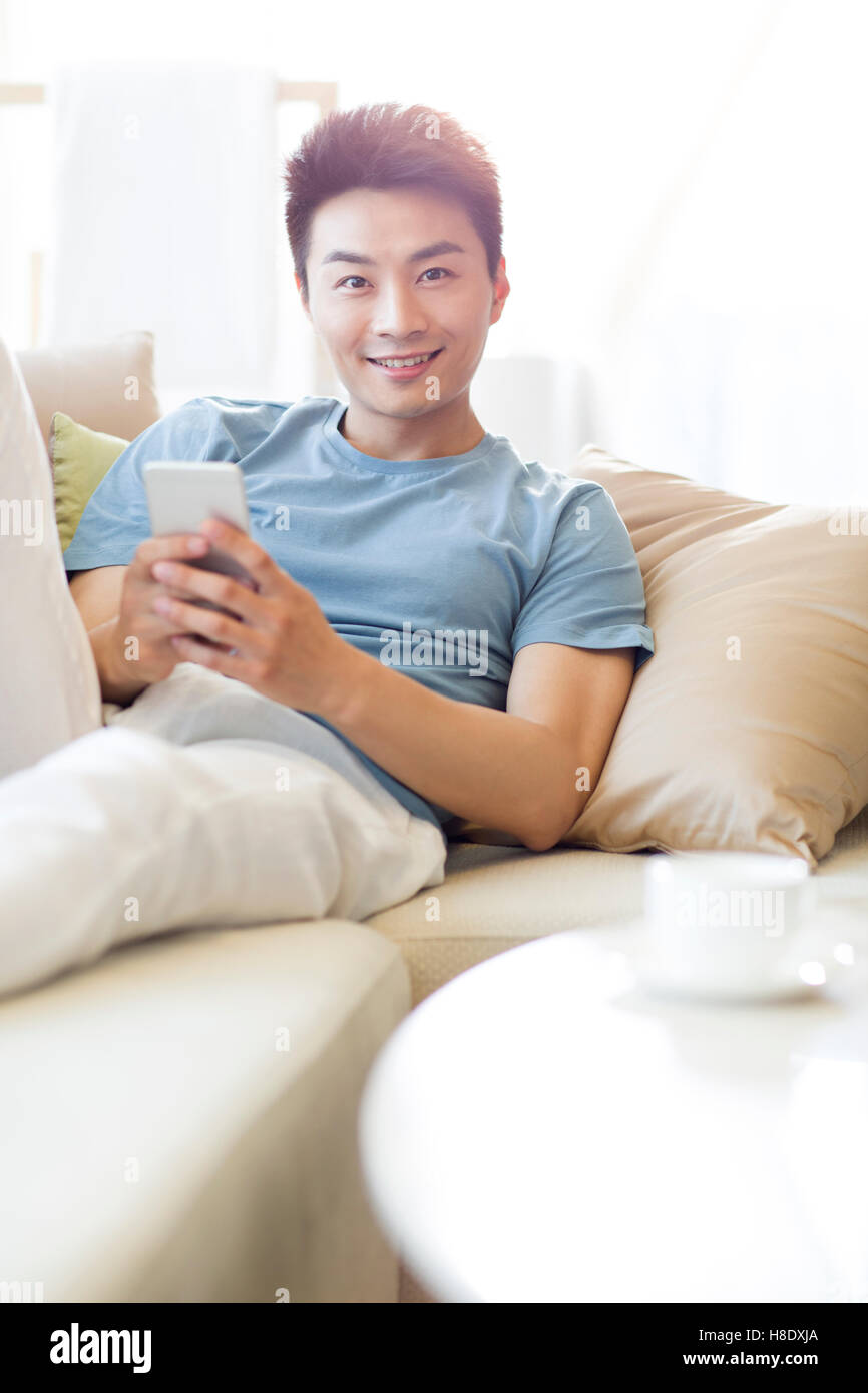 Young Chinese man relaxing on the sofa Stock Photo - Alamy