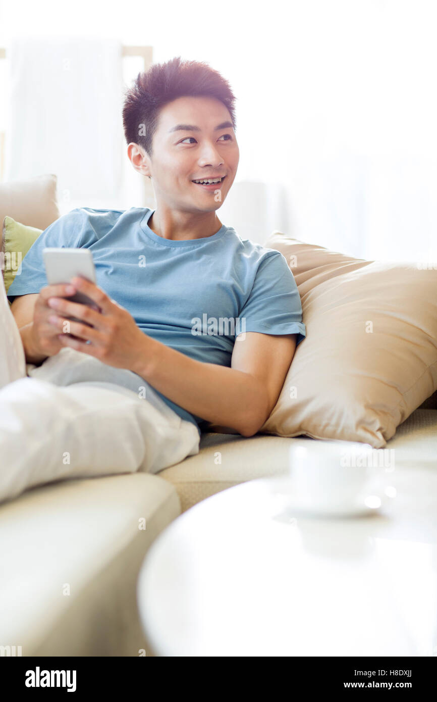 Young Chinese man relaxing on the sofa Stock Photo - Alamy
