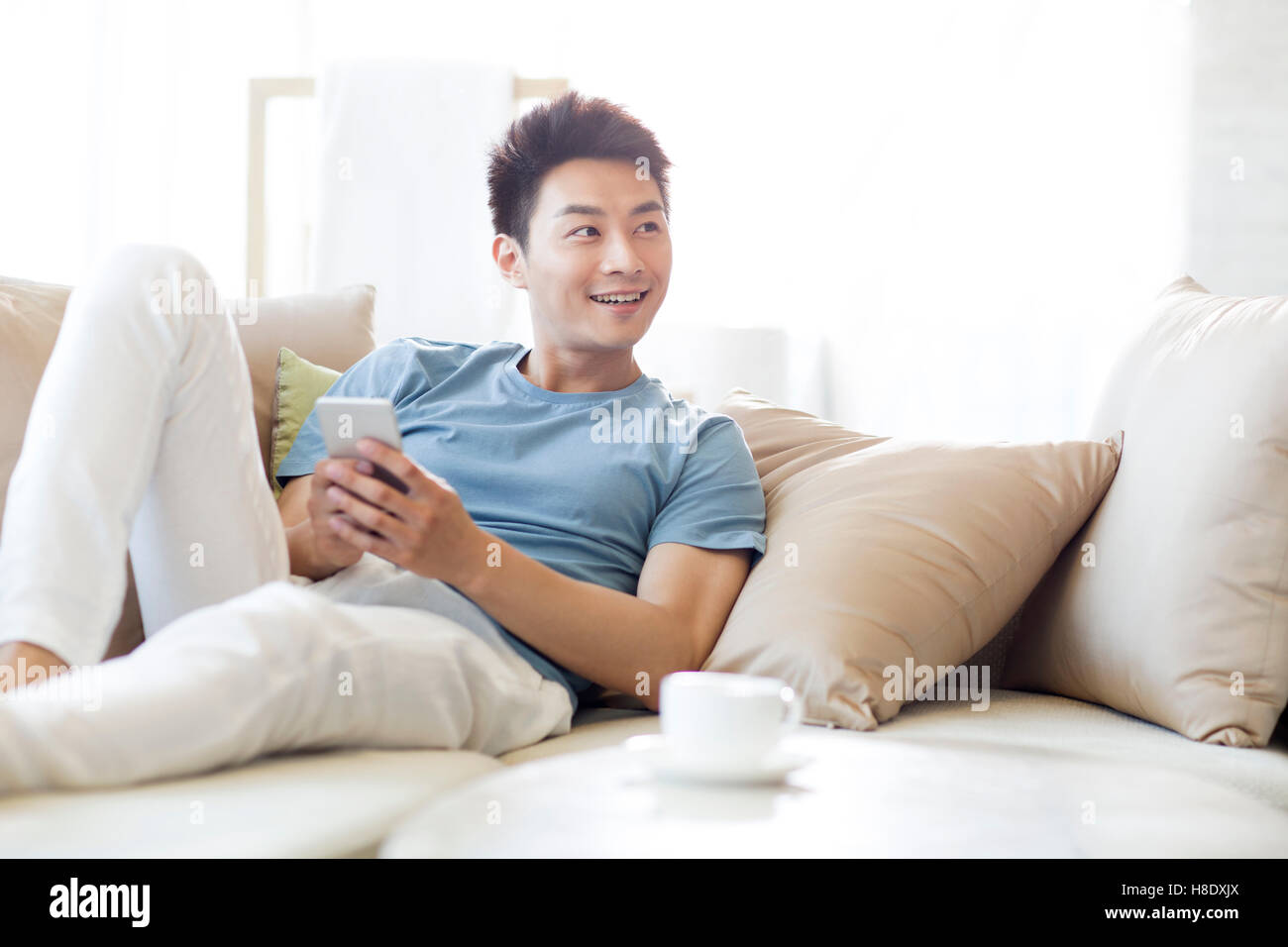 Young Chinese man relaxing on the sofa Stock Photo - Alamy