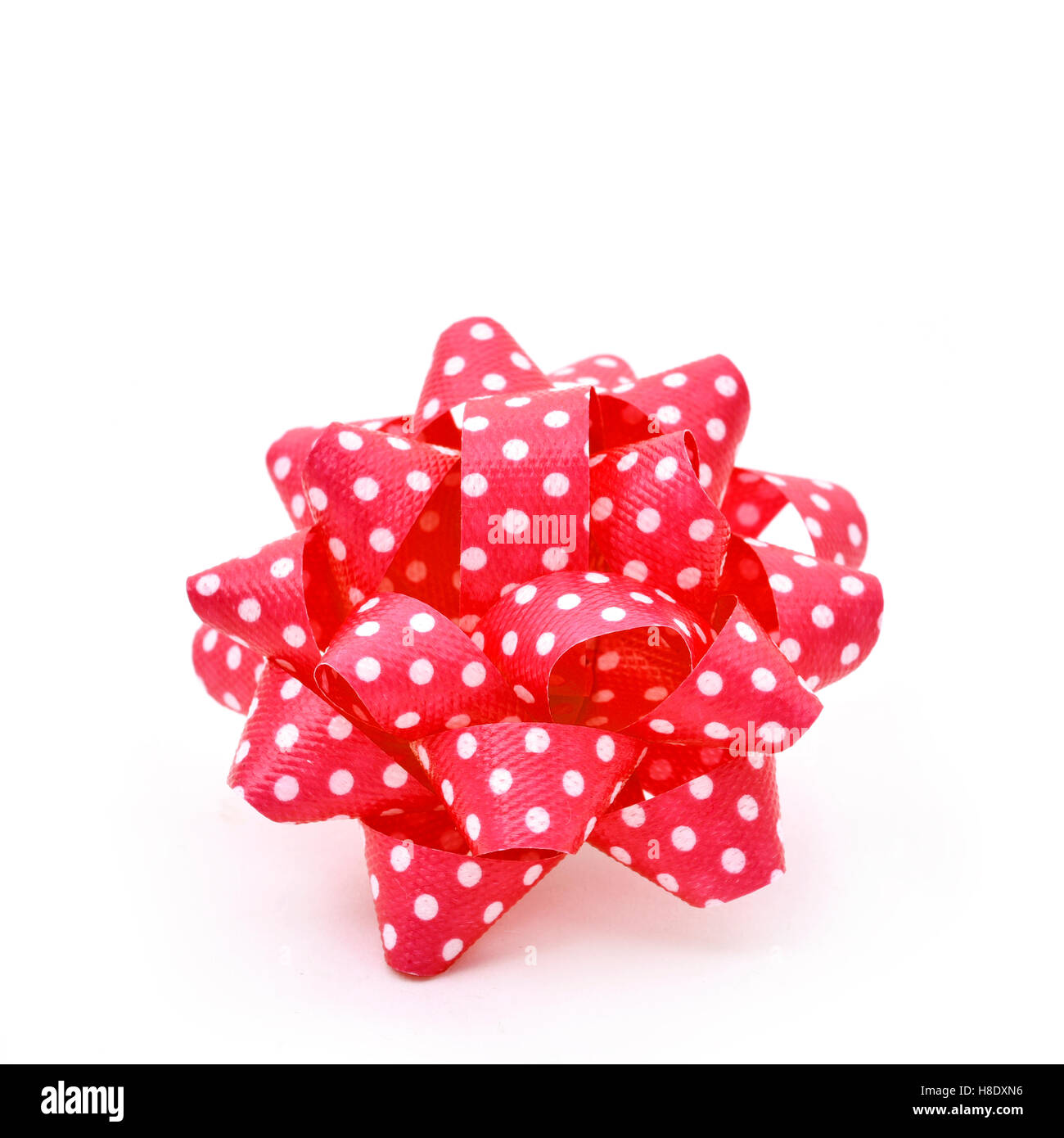 a gift puff bow made with red ribbon patterned with white dots, on a ...