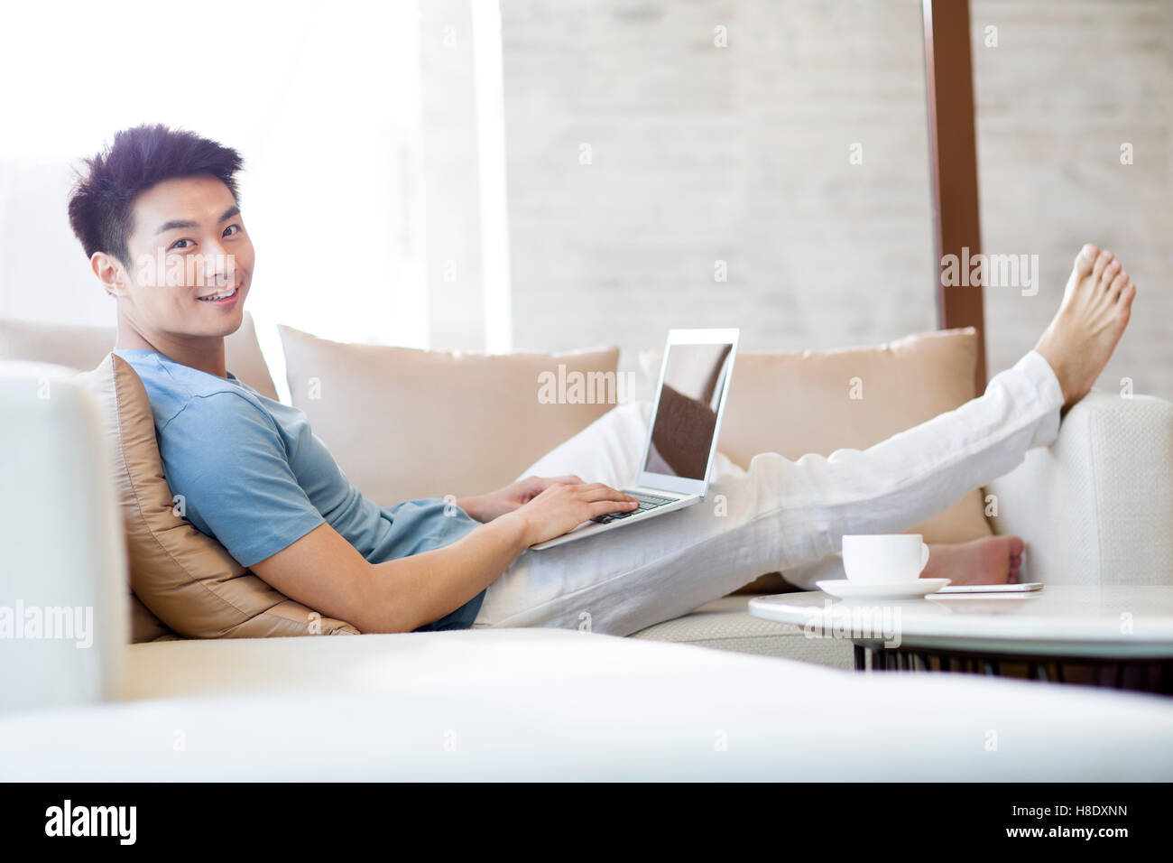 Young Chinese man using laptop on the sofa Stock Photo - Alamy