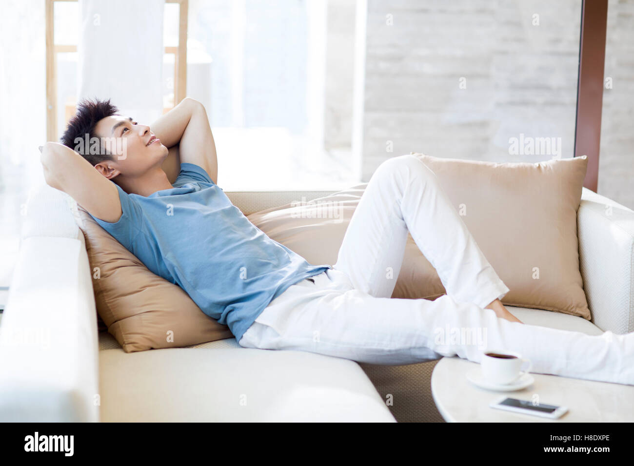 Young Chinese man relaxing on the sofa Stock Photo - Alamy
