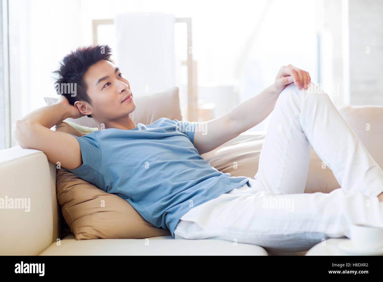 Young Chinese man relaxing on the sofa Stock Photo - Alamy