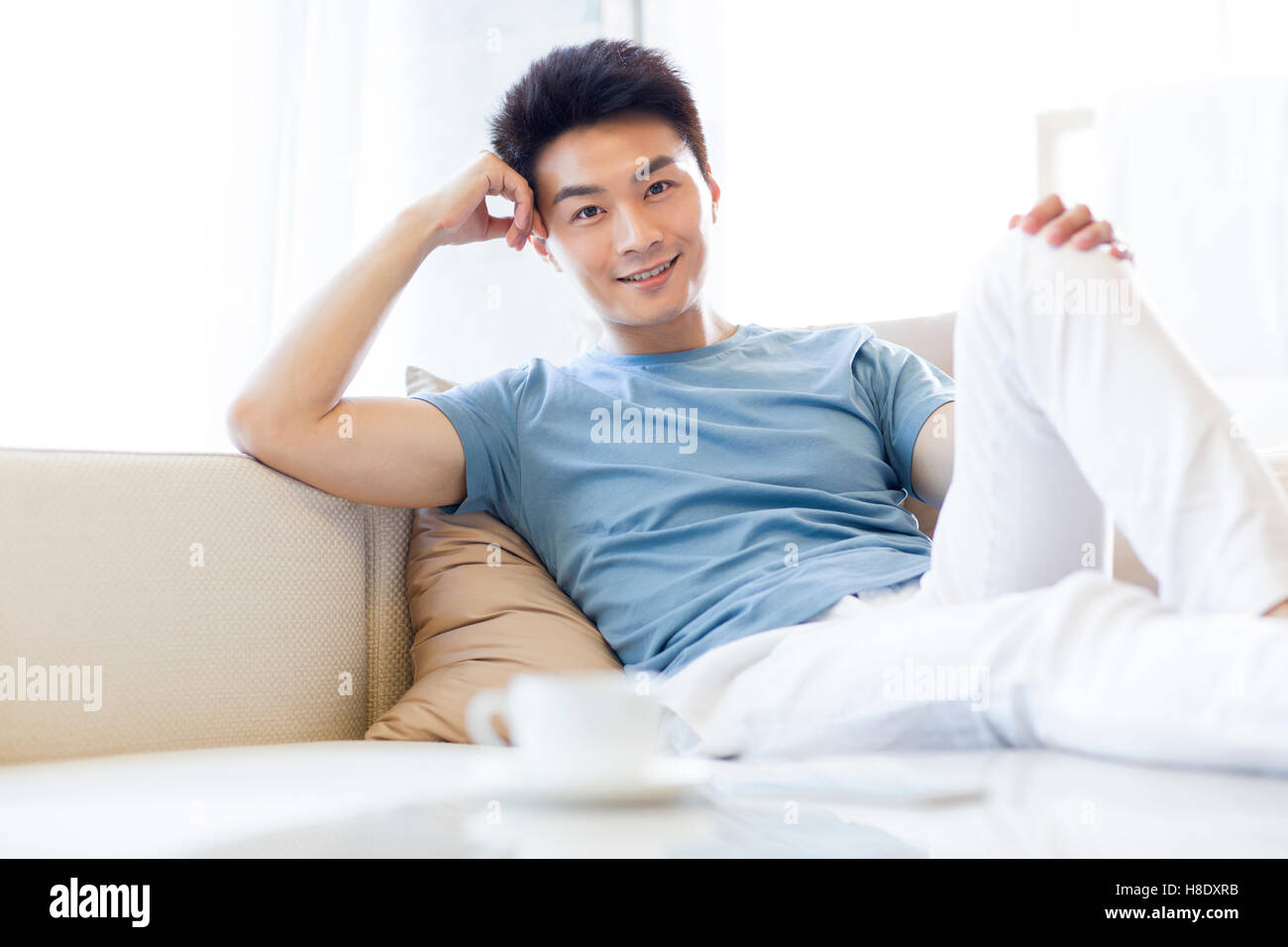 Young Chinese man relaxing on the sofa Stock Photo - Alamy