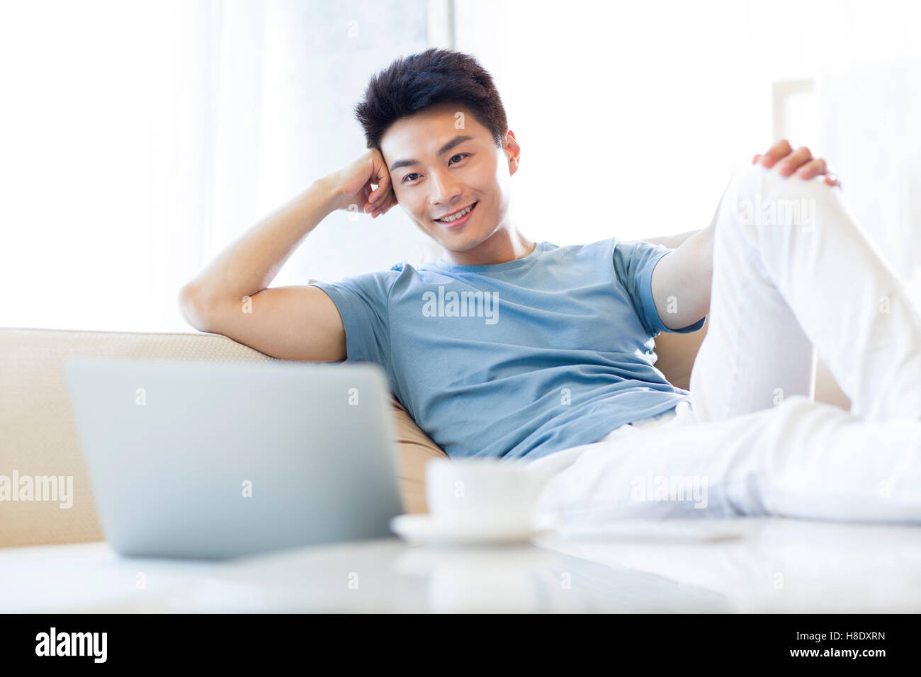 Young Chinese man using laptop on the sofa Stock Photo - Alamy