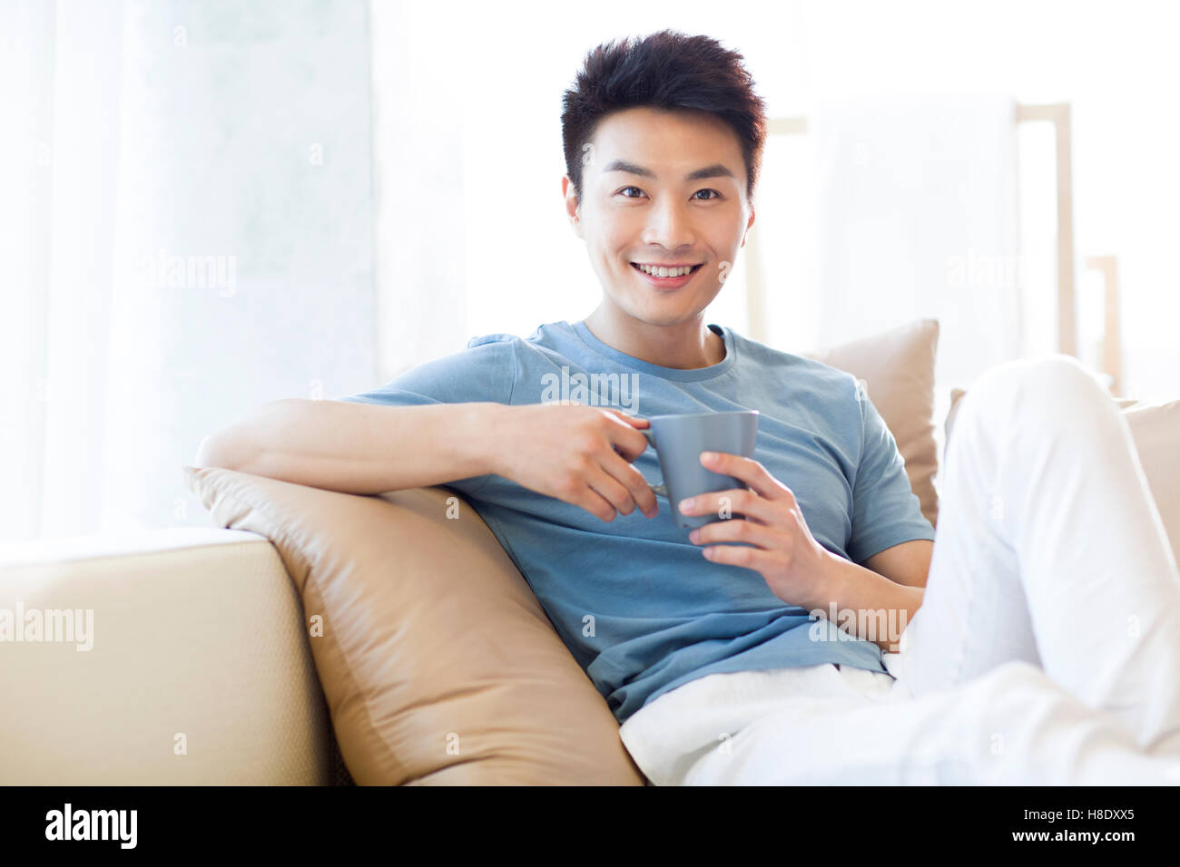 Young Chinese man drinking coffee at home Stock Photo - Alamy