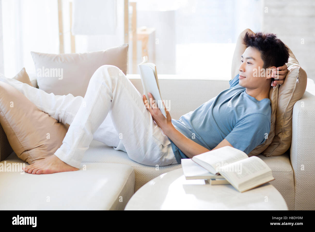 Young Chinese man reading a book on the sofa Stock Photo - Alamy