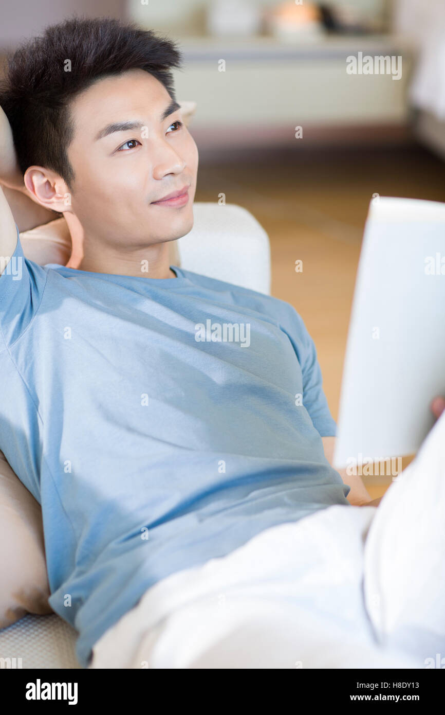 Young Chinese man reading a book on the sofa Stock Photo - Alamy