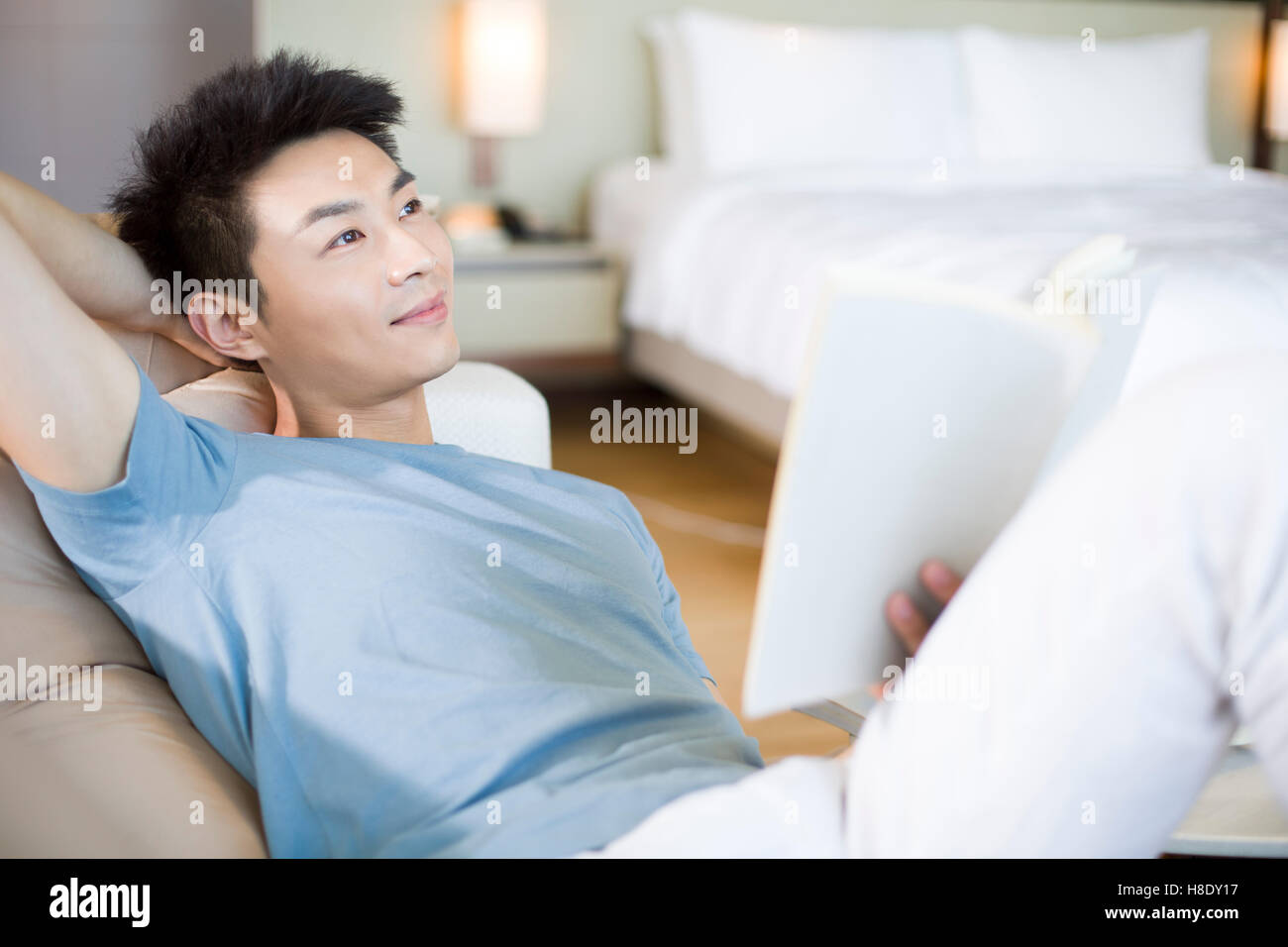 Young Chinese man reading a book on the sofa Stock Photo - Alamy
