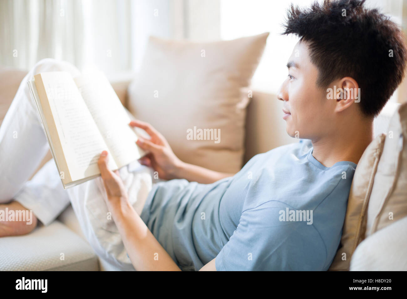 Young Chinese man reading a book on the sofa Stock Photo - Alamy