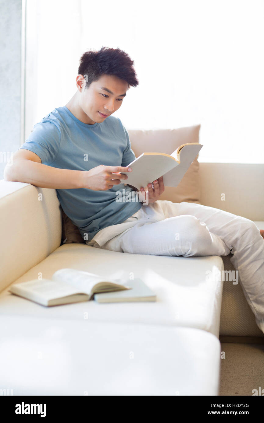 Young Chinese man reading a book on the sofa Stock Photo - Alamy