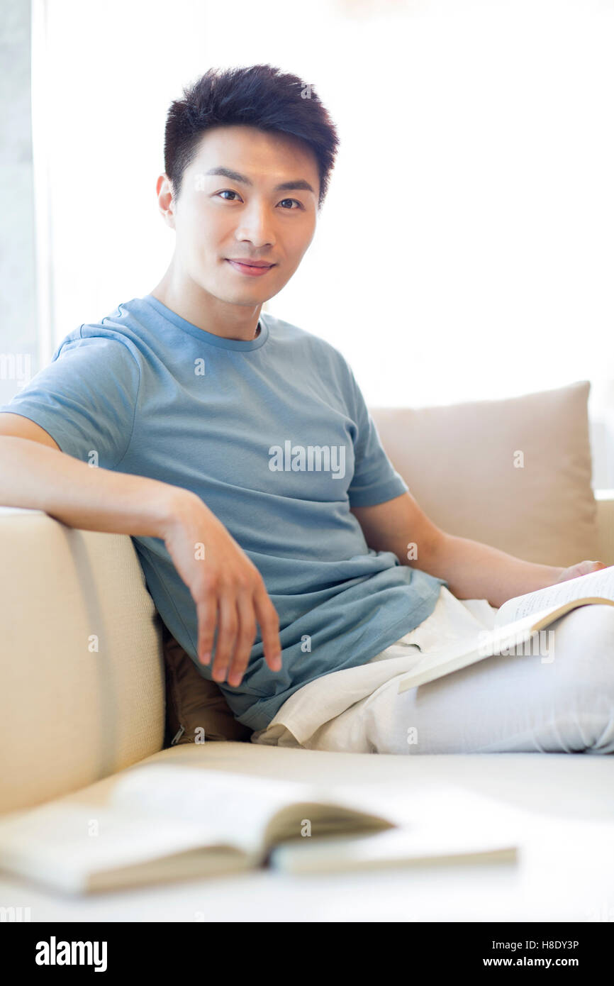 Young Chinese man reading a book on the sofa Stock Photo - Alamy