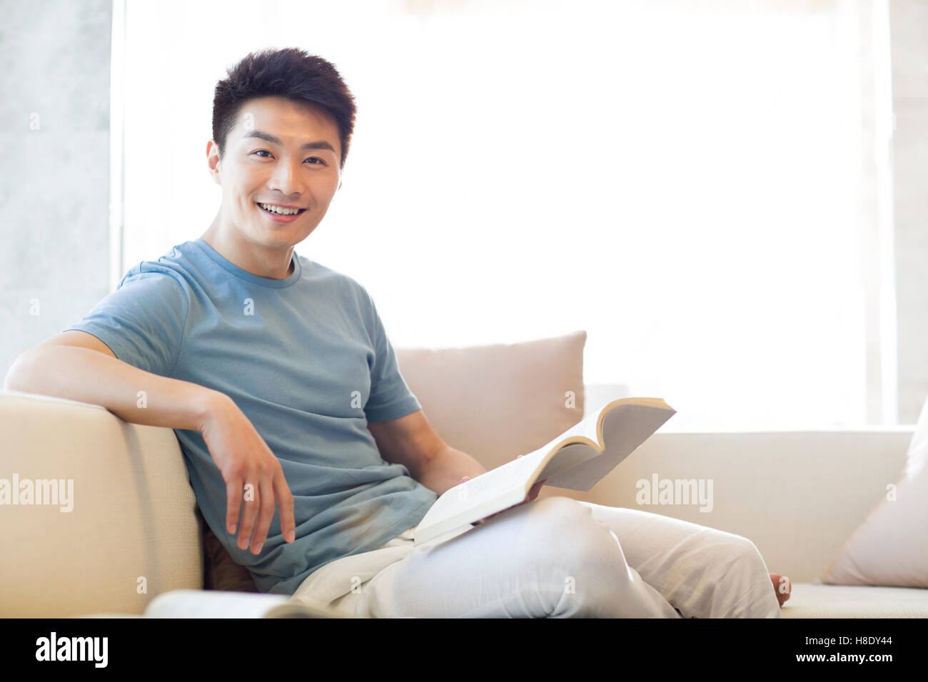 Young Chinese man reading a book on the sofa Stock Photo - Alamy