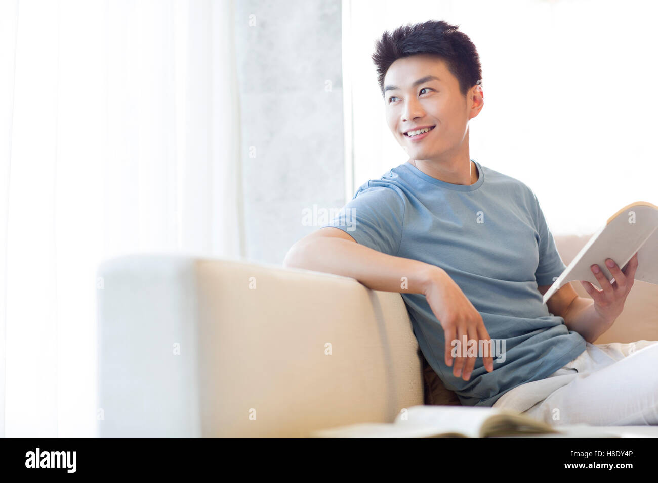Young Chinese man reading a book on the sofa Stock Photo - Alamy