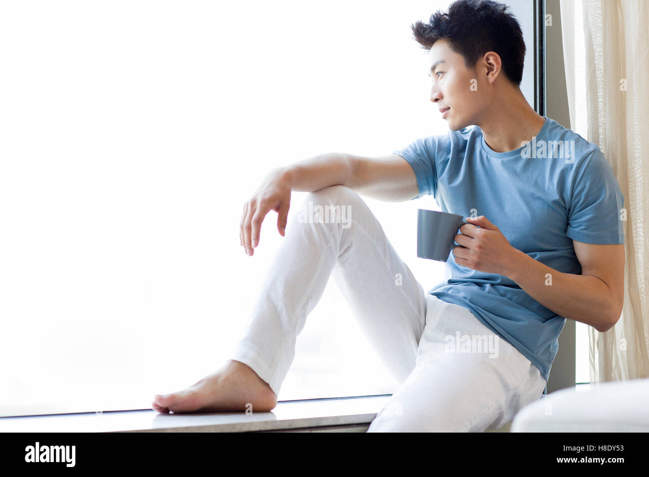 Young Chinese man drinking coffee at home Stock Photo - Alamy