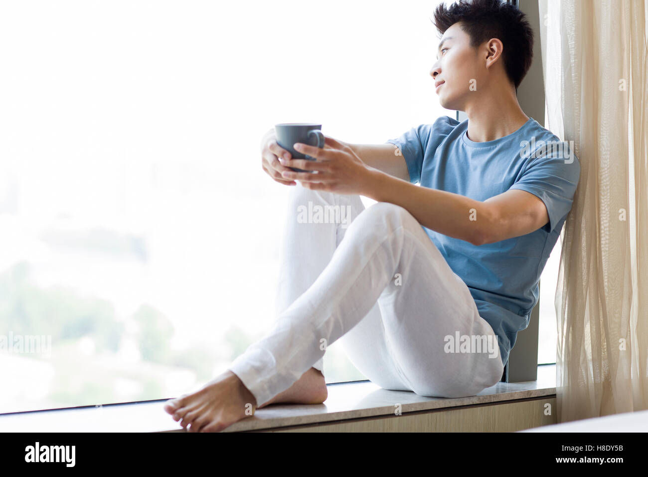 Young Chinese man drinking coffee at home Stock Photo - Alamy