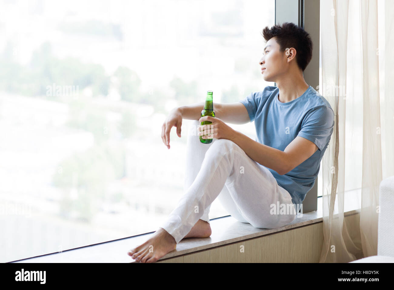 Young Chinese man drinking beer at home Stock Photo - Alamy