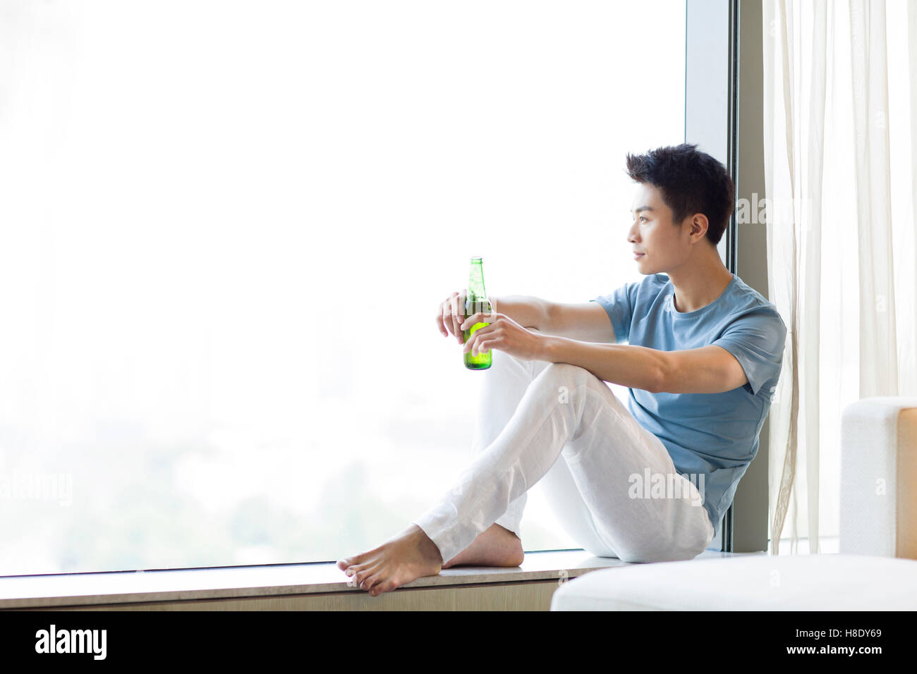 Young Chinese man drinking beer at home Stock Photo - Alamy