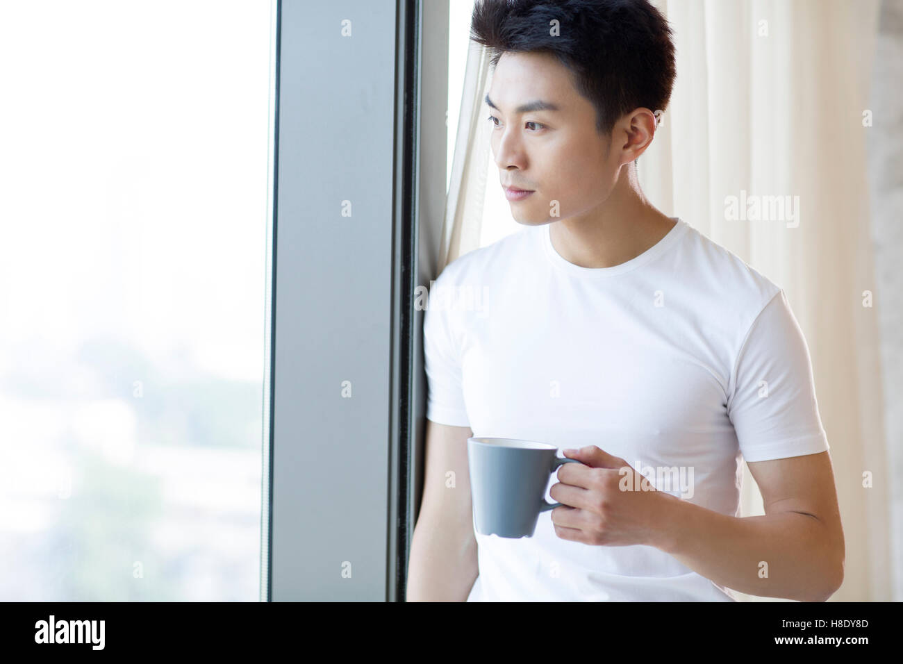 Young Chinese man drinking coffee at home Stock Photo - Alamy