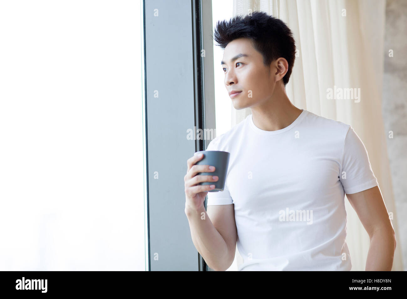 Young Chinese man drinking coffee at home Stock Photo - Alamy