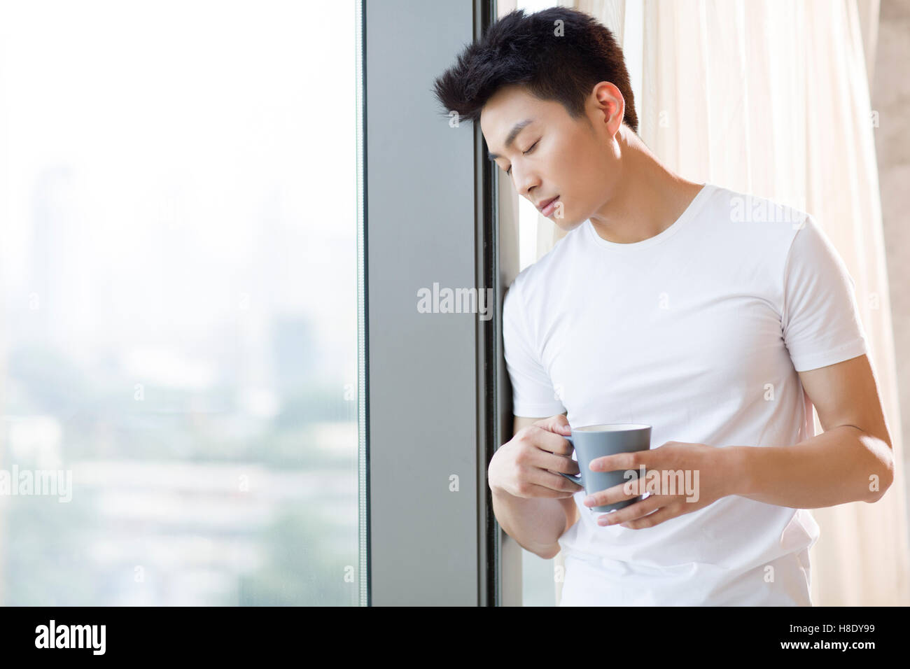 Young Chinese man drinking coffee at home Stock Photo - Alamy