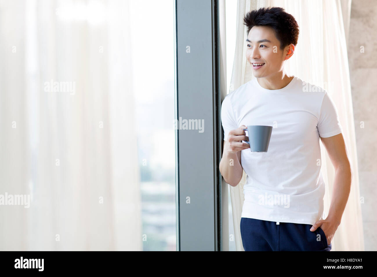 Young Chinese man drinking coffee at home Stock Photo - Alamy