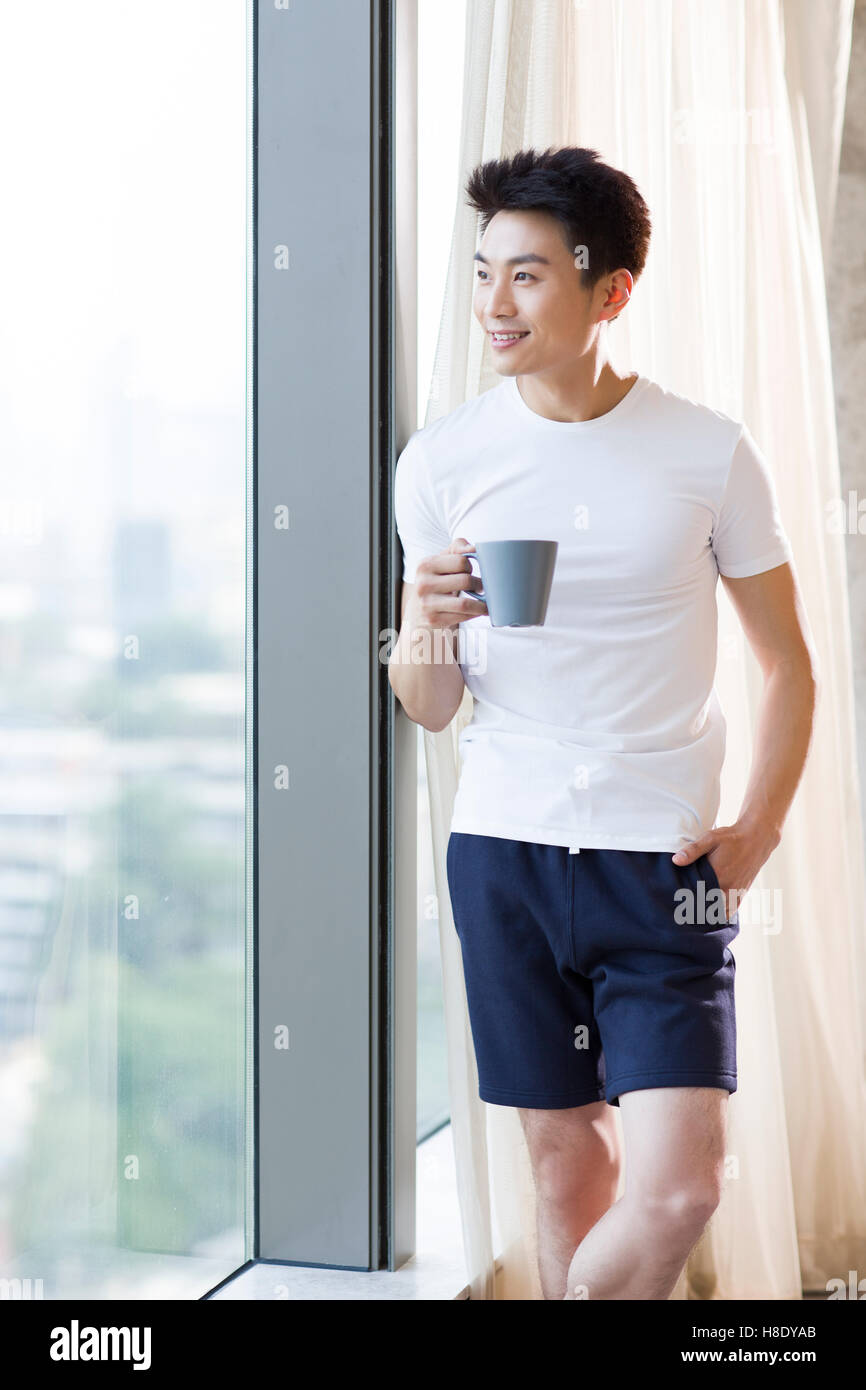 Young Chinese man drinking coffee at home Stock Photo - Alamy