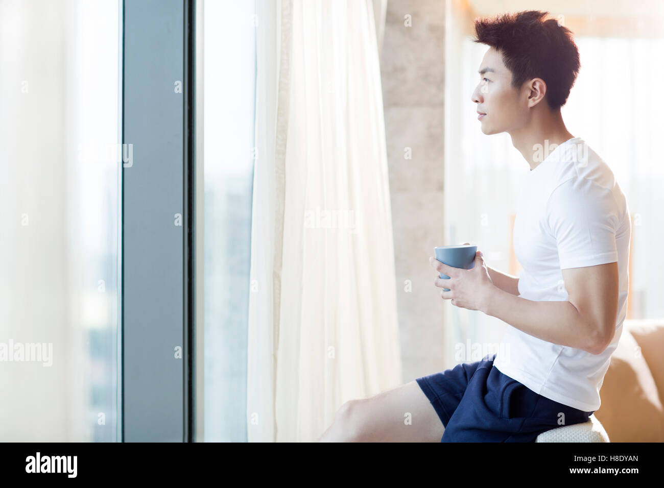 Young Chinese man drinking coffee at home Stock Photo - Alamy