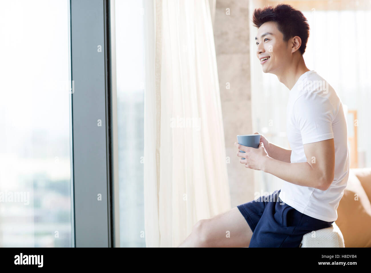Young Chinese man drinking coffee at home Stock Photo - Alamy
