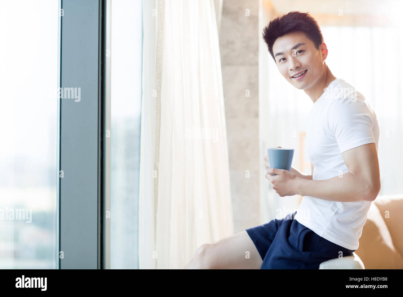 Young Chinese man drinking coffee at home Stock Photo - Alamy