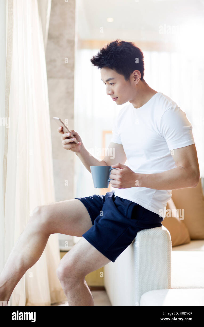 Young Chinese man using smart phone at home Stock Photo - Alamy