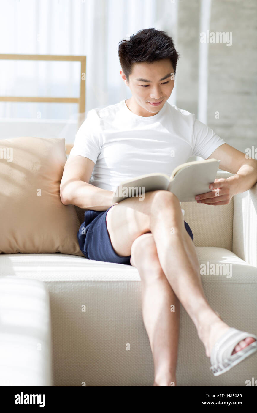 Young Chinese man reading a book on the sofa Stock Photo - Alamy
