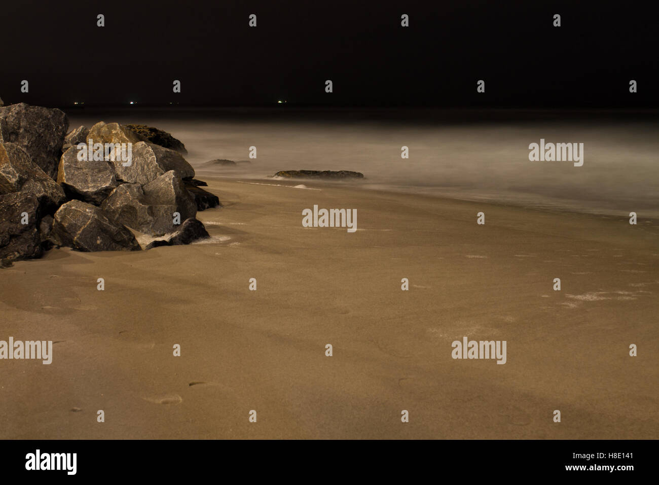 Coastal ocean rocks in a dark with black night sky and fog.Long ...