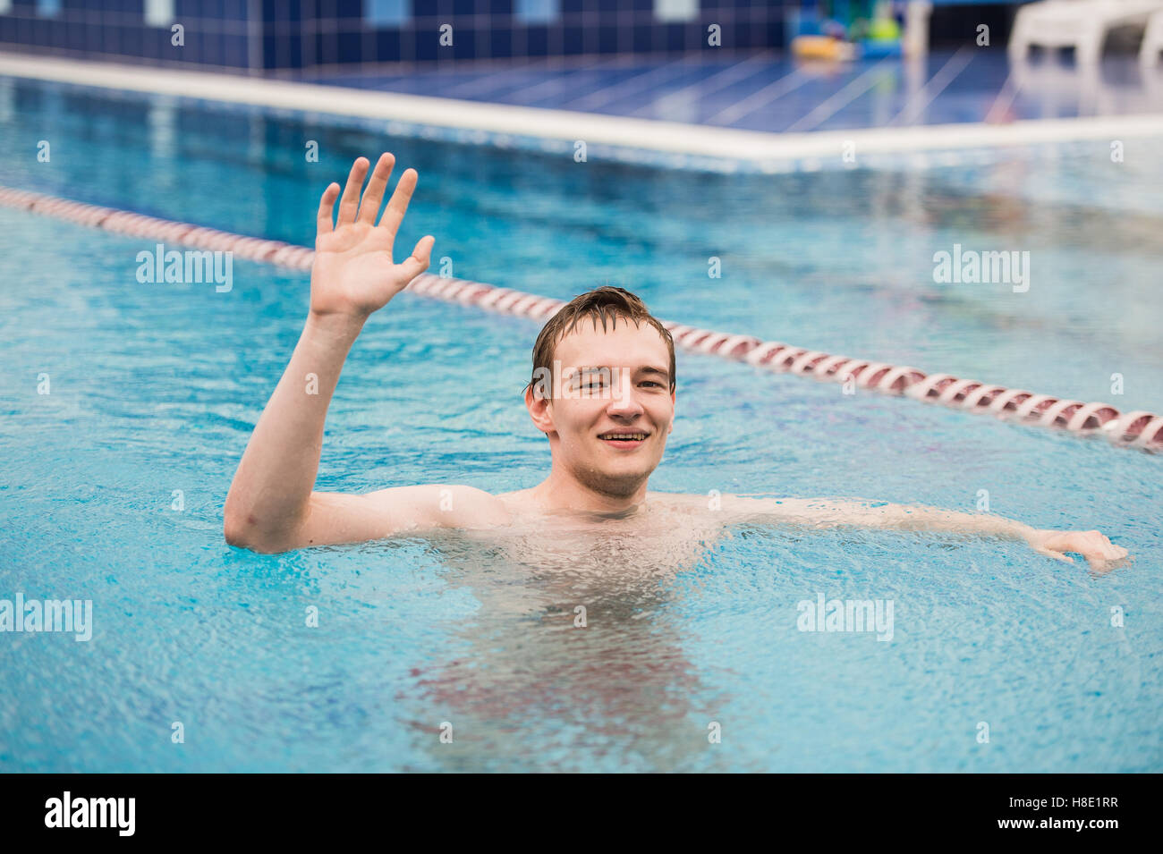 Young happy man in the swimming pool with one hand up cheering Stock ...