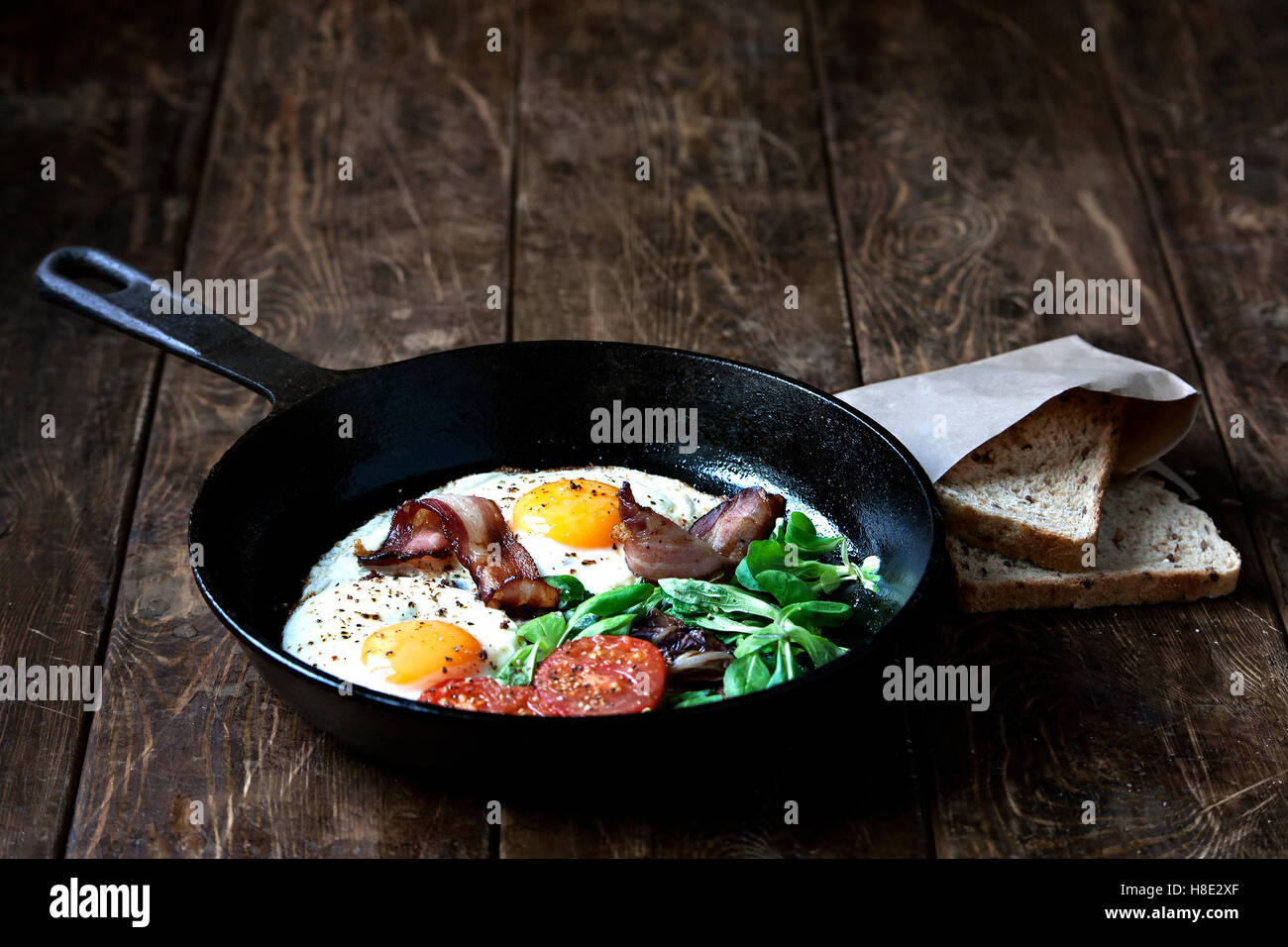 Breakfast set. Pan of fried eggs with bacon, fresh tomato, sage and ...