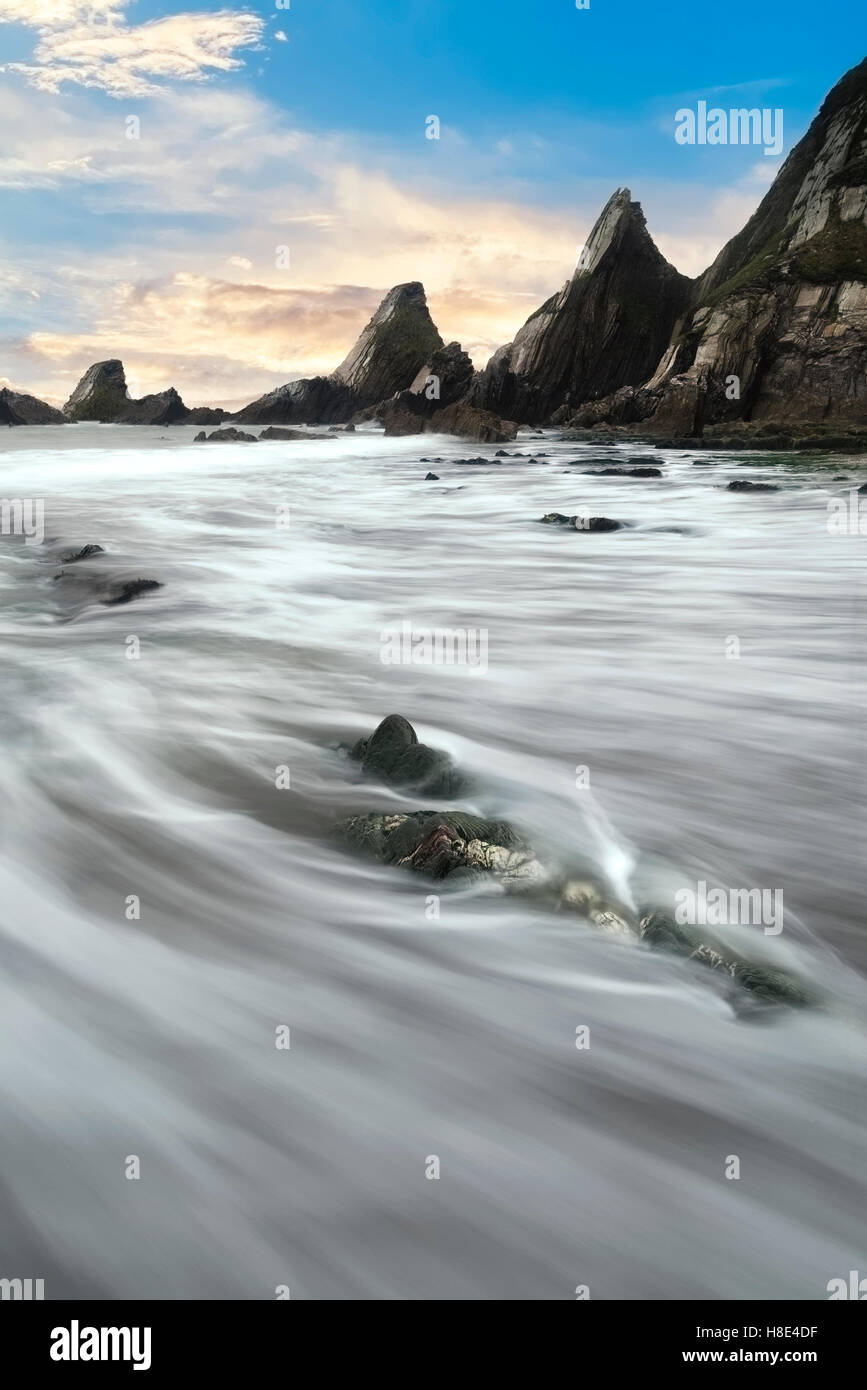 Beautiful colorful sunset over beach landscape with jagged rock ...