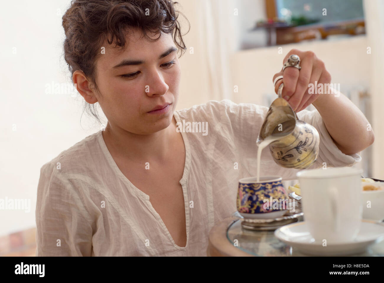 Asian woman holding a creamer and pouring milk into tea Stock Photo - Alamy