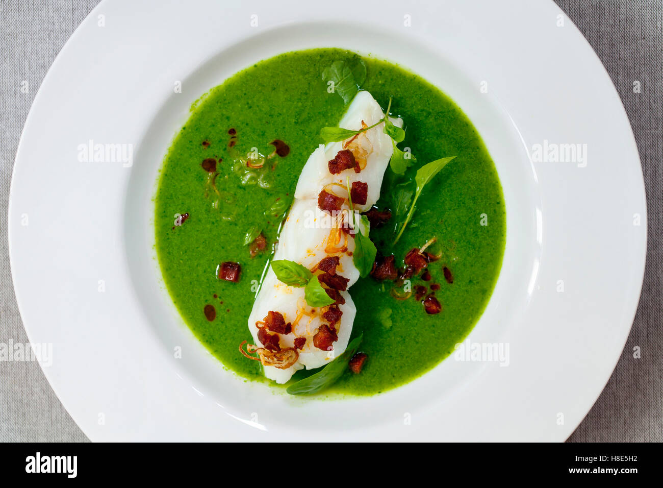 Butter poached cod with green peas, spinach and basil veloute, crispy ...