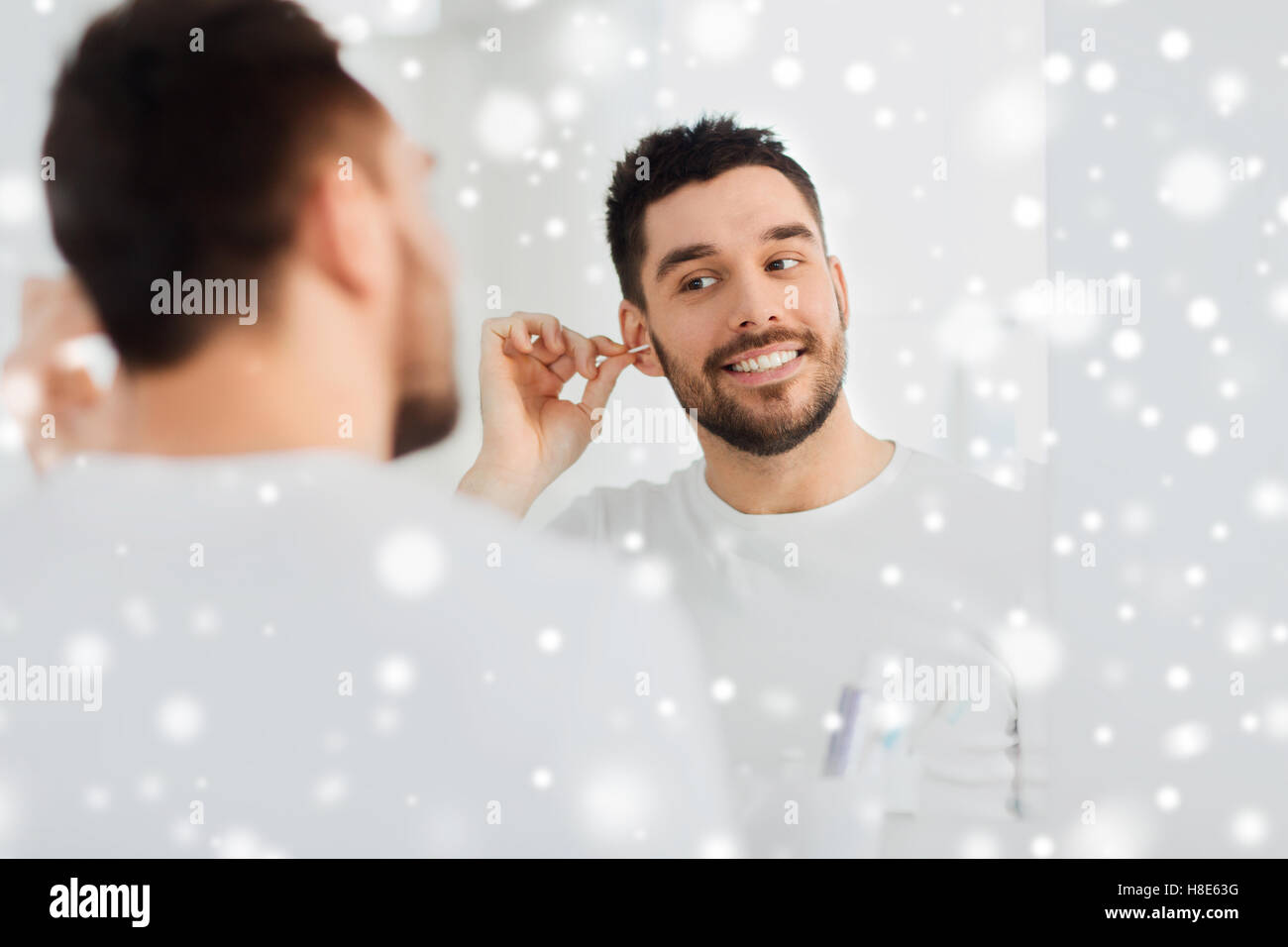 man cleaning ear with cotton swab at bathroom Stock Photo - Alamy