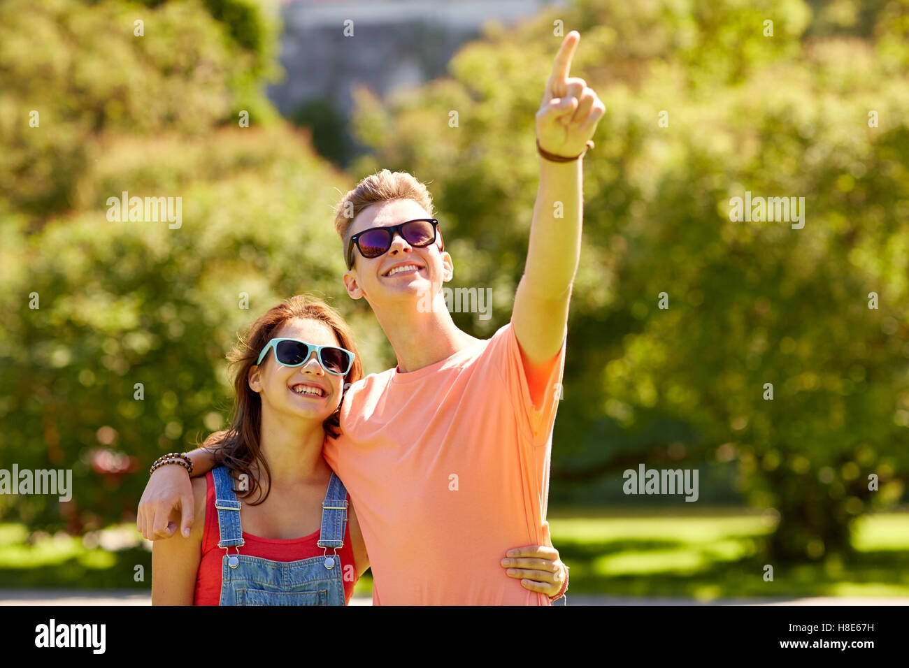 happy couple pointing finger at summer park Stock Photo - Alamy