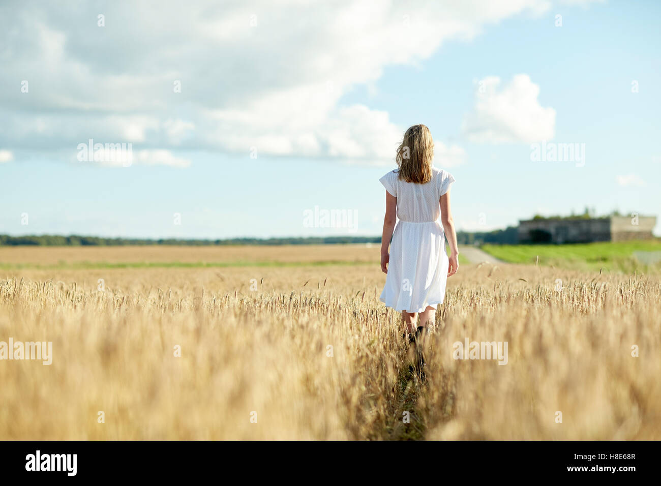 young woman in white dress walking along on field Stock Photo - Alamy