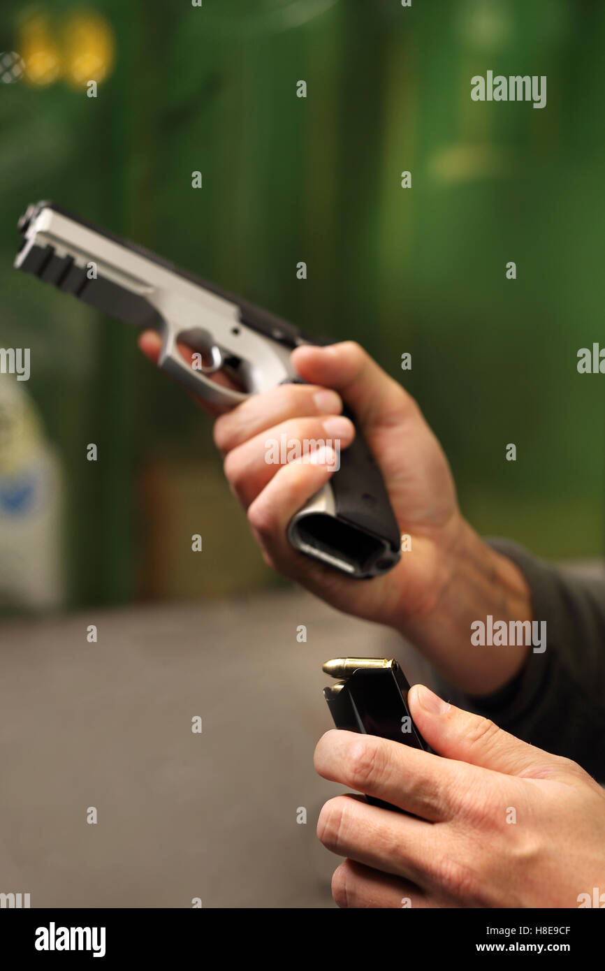Shooting a gun at a shooting range. The man at the shooting reloads ...