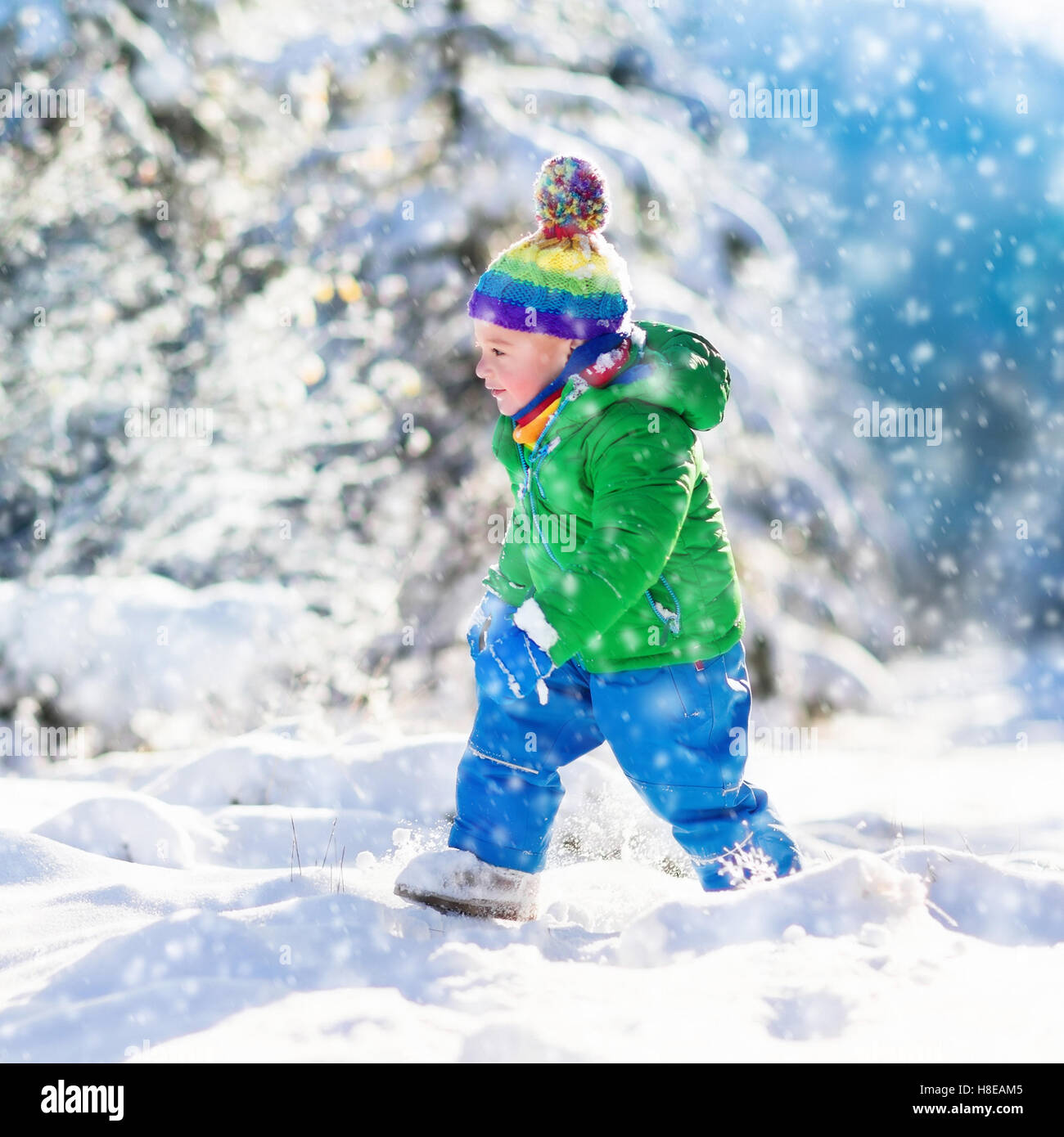 Child running in snowy forest. Toddler kid playing outdoors. Kids play ...