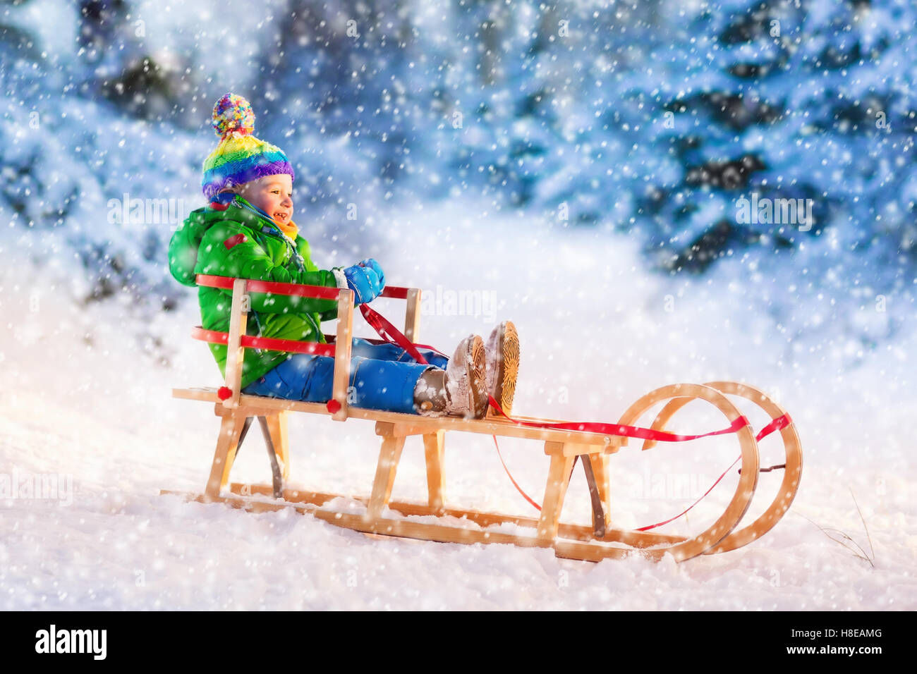Little boy enjoying sleigh ride. Child sledding. Toddler kid riding a ...