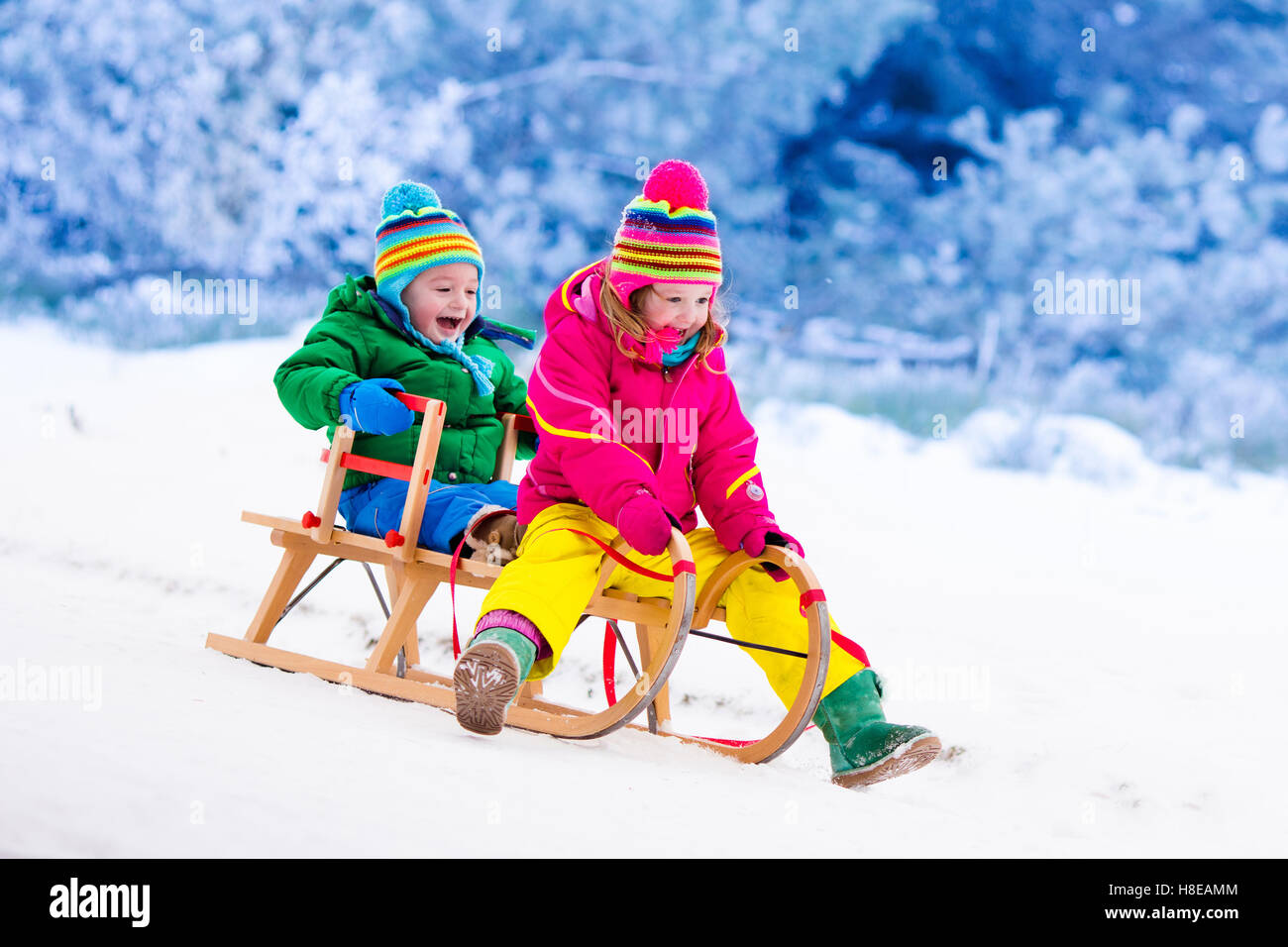Little girl and boy enjoying sleigh ride. Child sledding. Toddler kid riding a sledge. Children ...